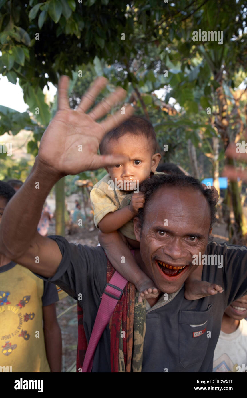 TIMOR LESTE Man (with betel nut stained mouth) carrying child and ...