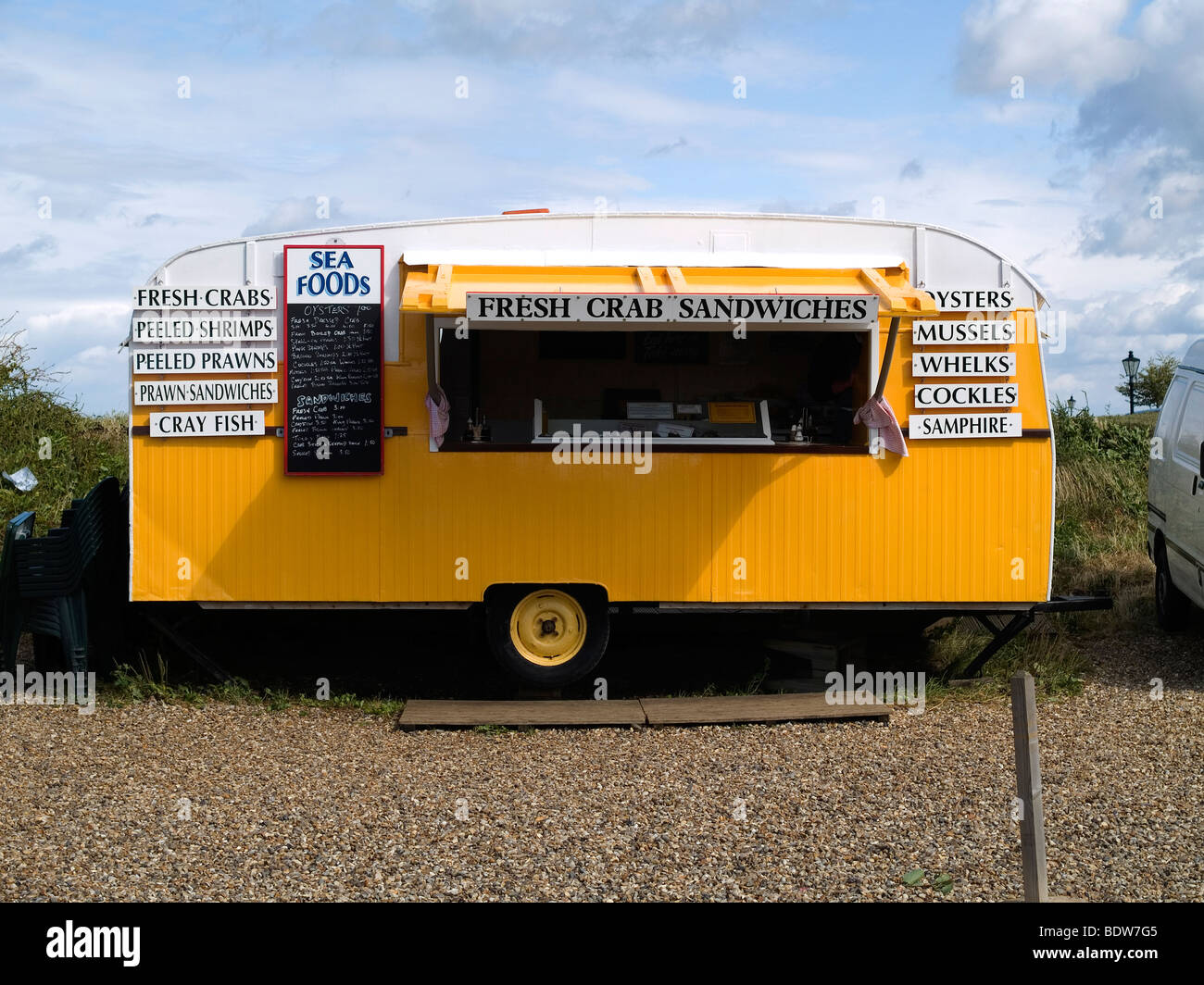 A bright yellow painted sea food caravan stall at Blakeney Norfolk ...