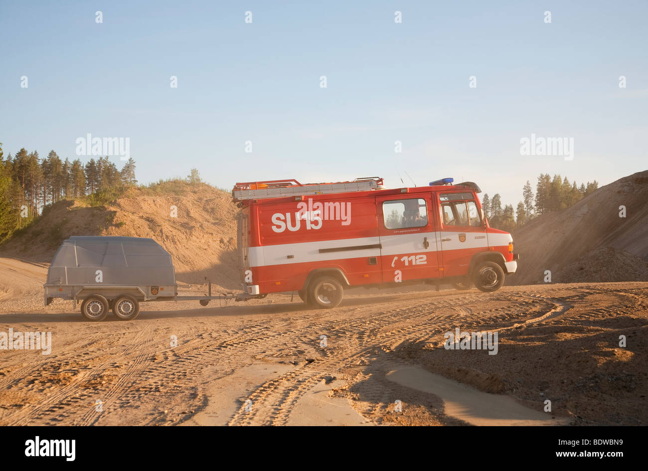 Fire department support vehicle with trailer driving on dirt road ...