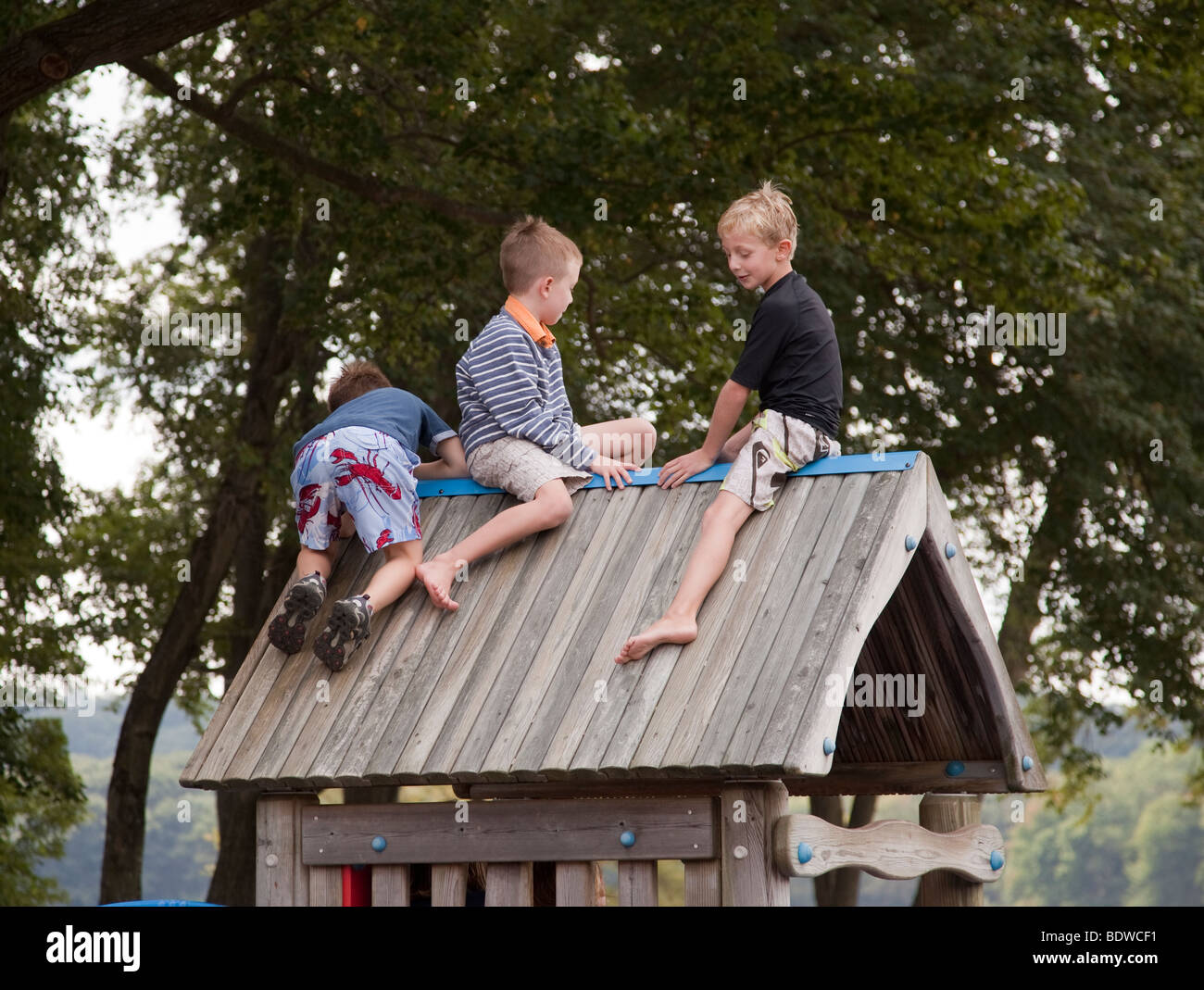 Three boys climbing on the roof of a playhouse Stock Photo - Alamy