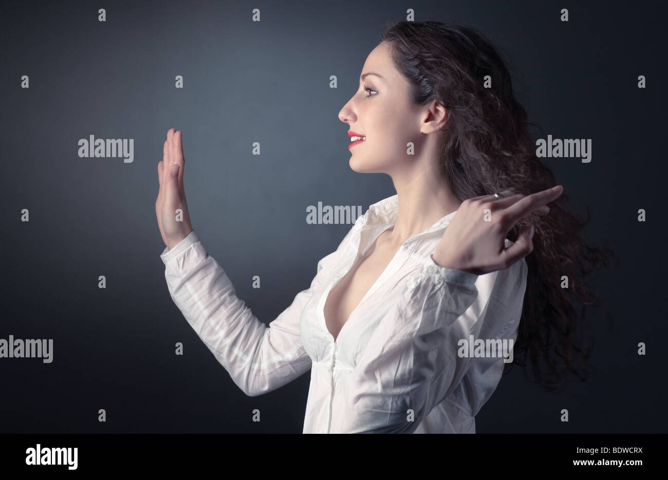 Young woman stretching hand. On dark background Stock Photo - Alamy