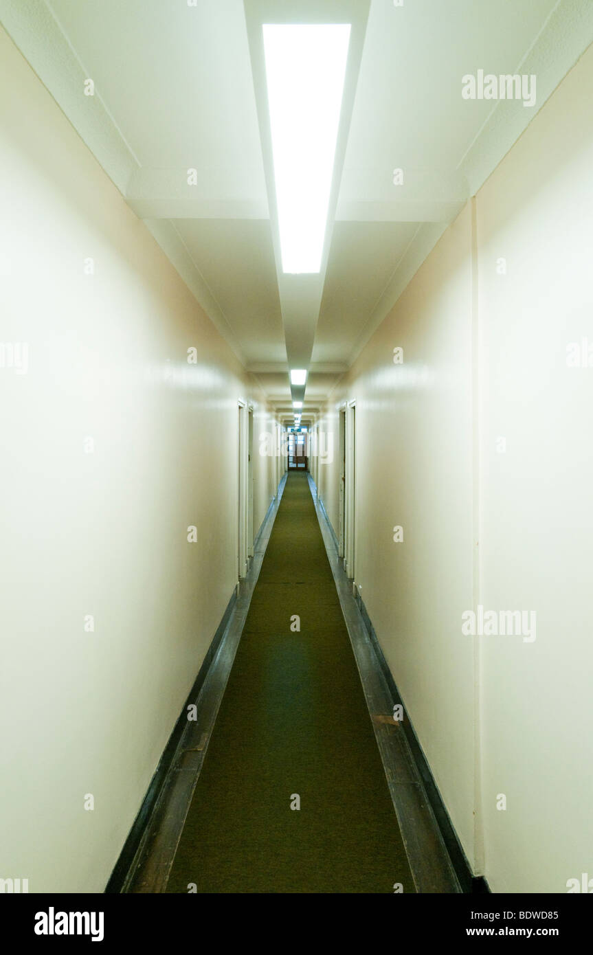 Artificial fluorescent lighting in long empty corridor in block of ...