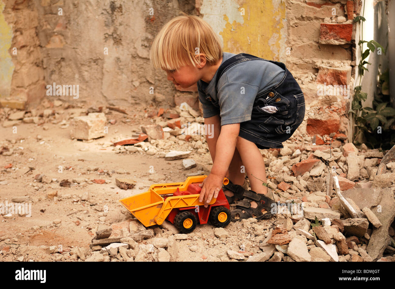 Little boy playing with a dredger in the rubble Stock Photo - Alamy