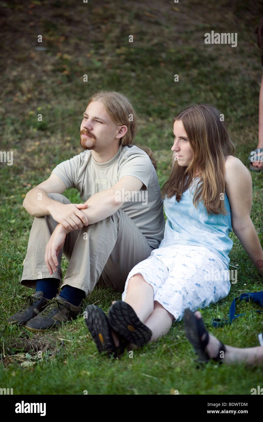 A young couple listen to a traditional folk music concert in a park in ...