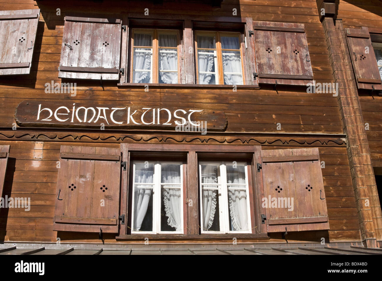 Typical wood house with scrollwork and lace curtans in Leukerbad, small ...