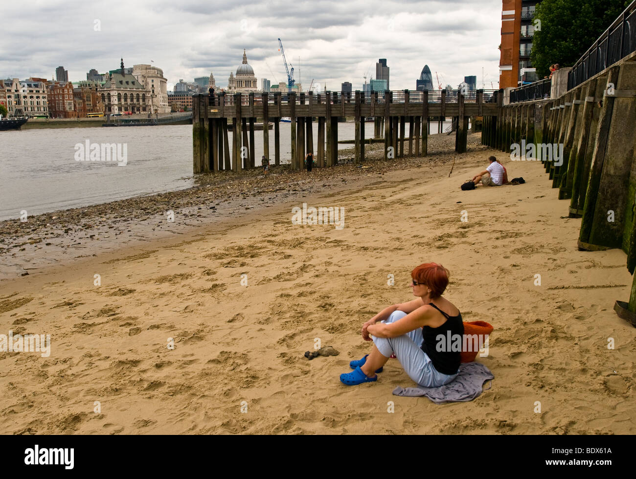 Two people relaxing on London's inner city river 'beach', River Thames ...
