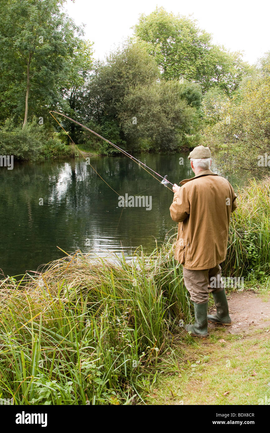 Trout fly fisherman catching a large rainbow trout, Avington Fishery ...