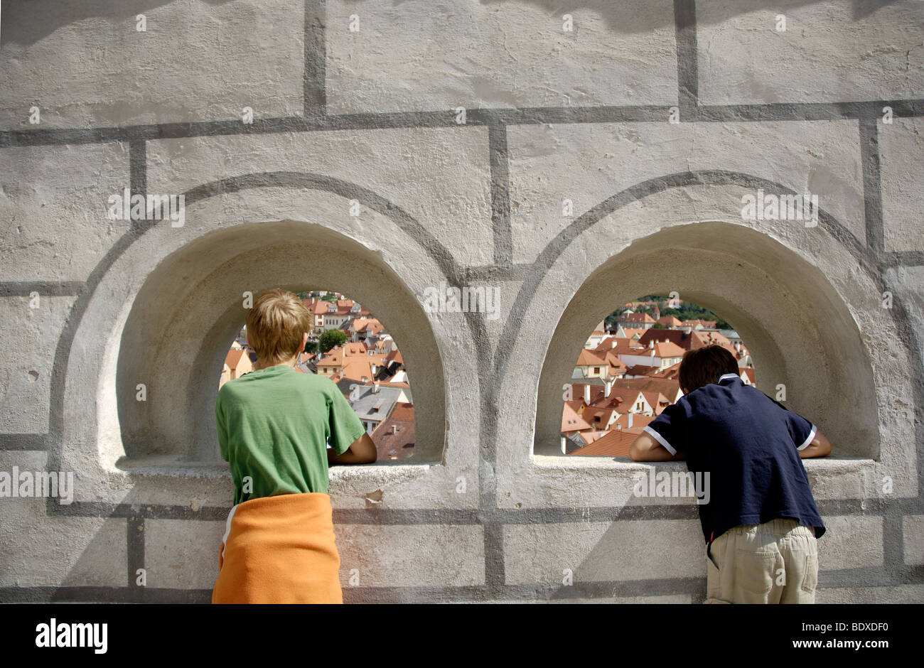 Two children looking through a window in the castle wall, Cesky Krumlov ...