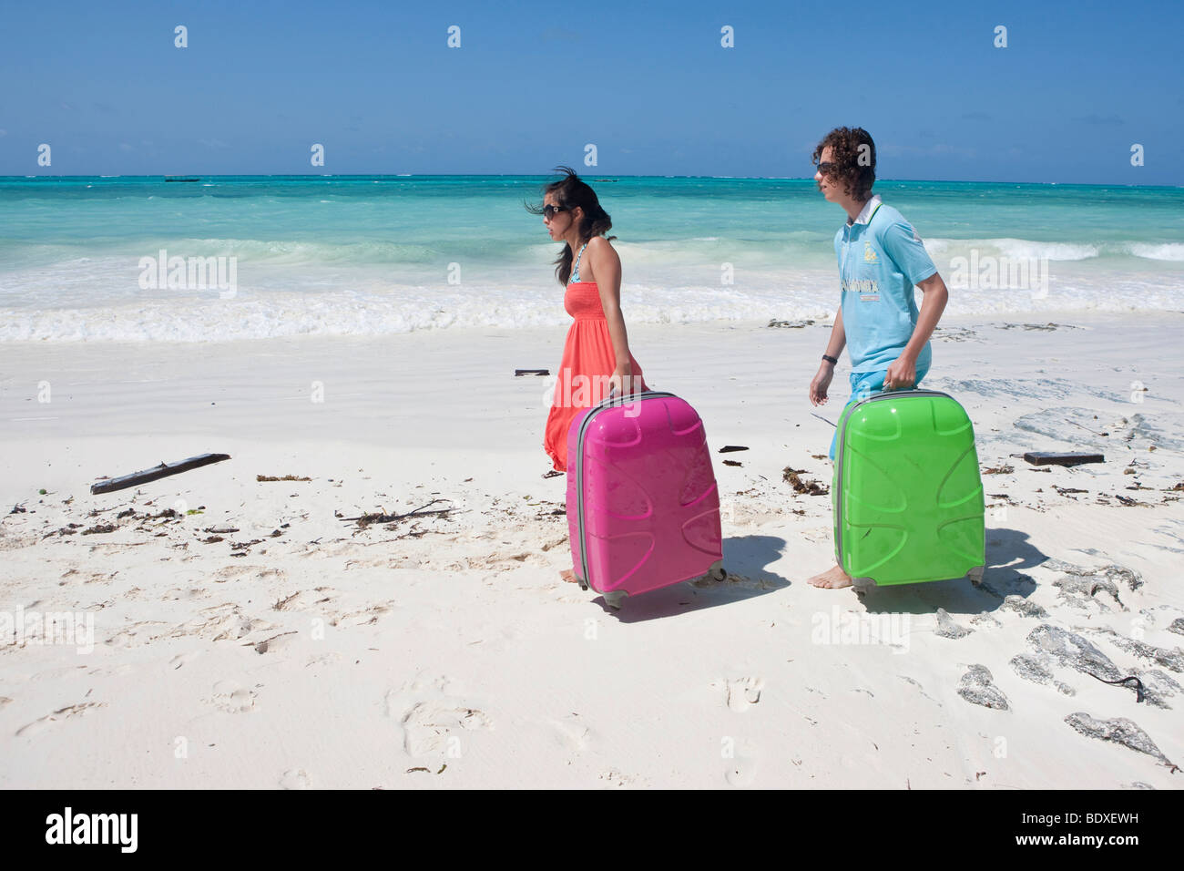 Two teenagers on holiday carry their suitcases at the beach Stock Photo ...