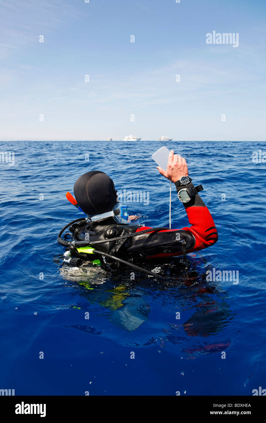 Drifting diver at sea is trying to get the attention of people on dive ...