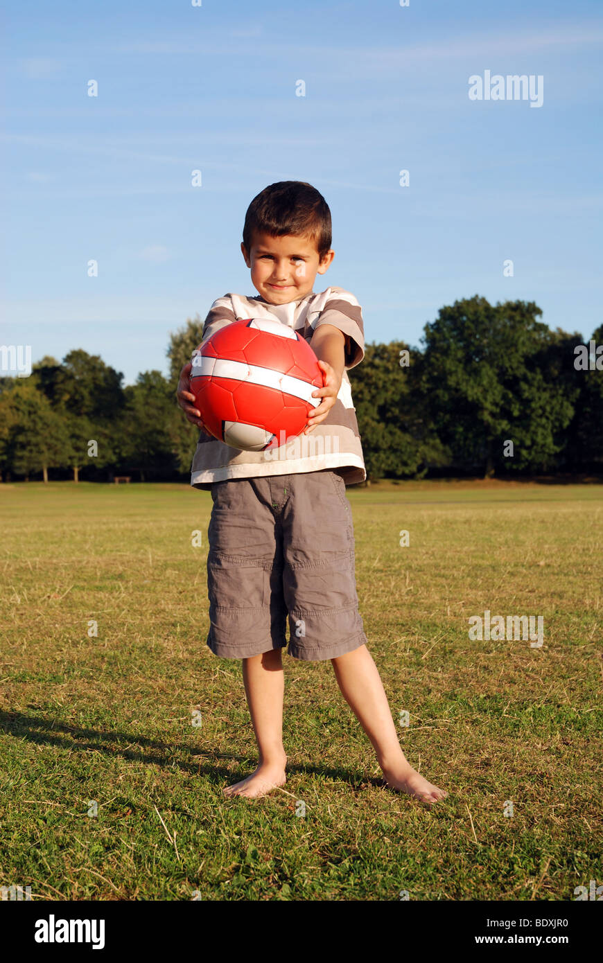Young boy holding ball Stock Photo - Alamy
