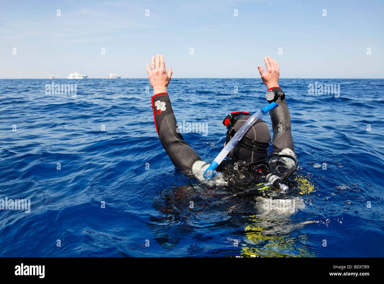 Drifting diver at sea is trying to get the attention of people on dive ...