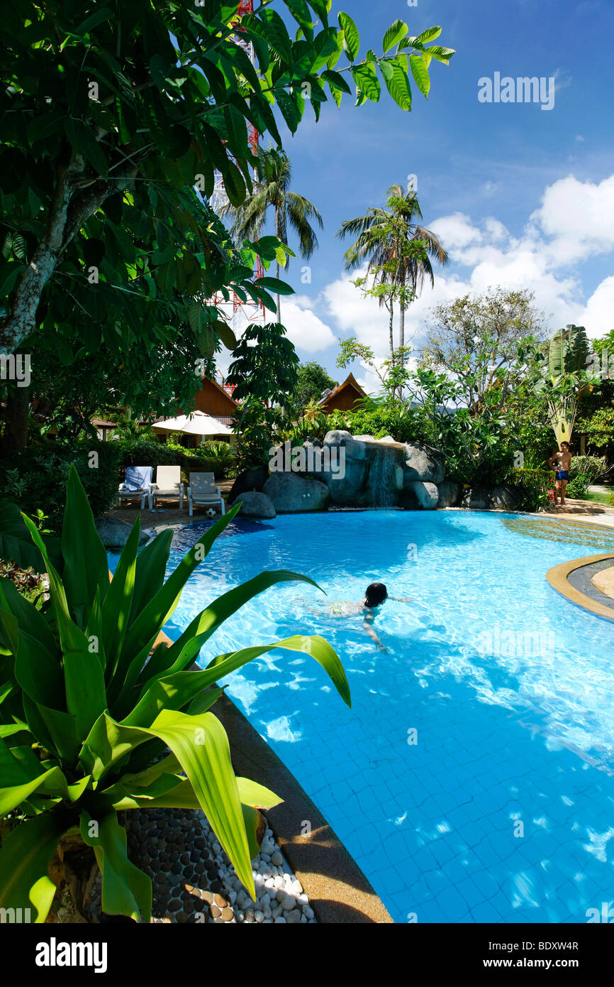 Bungalow resort with green surroundings and pool, sun chairs, high palm ...