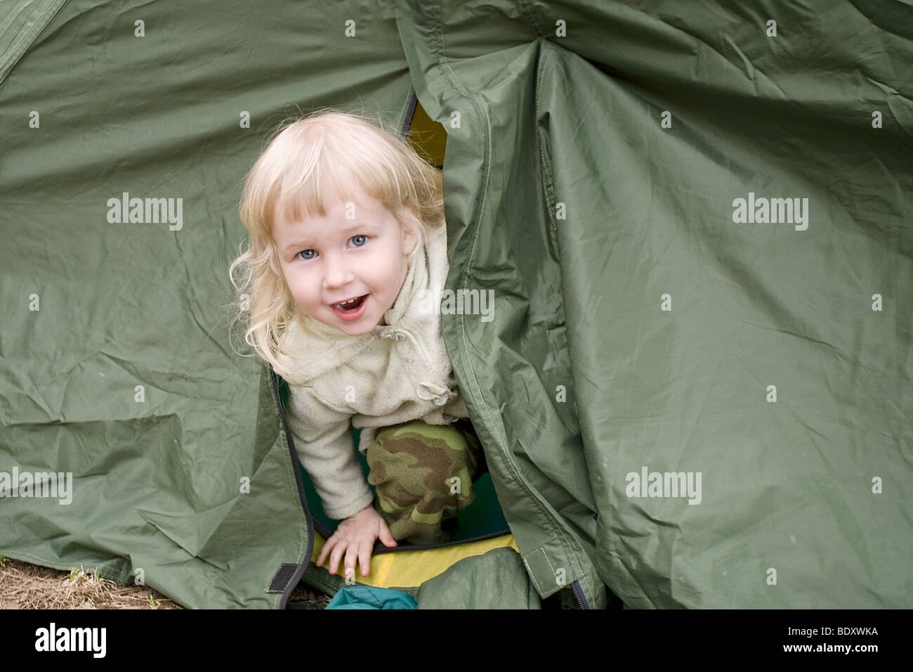 smiling little blonde girl getting out of tent Stock Photo - Alamy