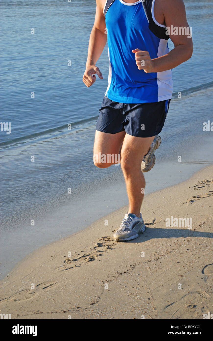 Man running jogging along a beach keeping fit Stock Photo - Alamy