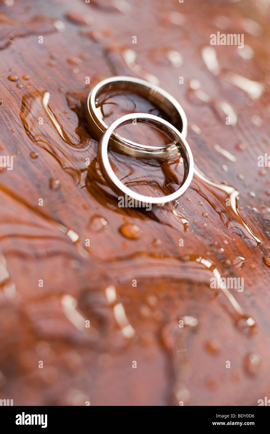 A pair of gold wedding rings on a wet polished wood surface Stock Photo ...