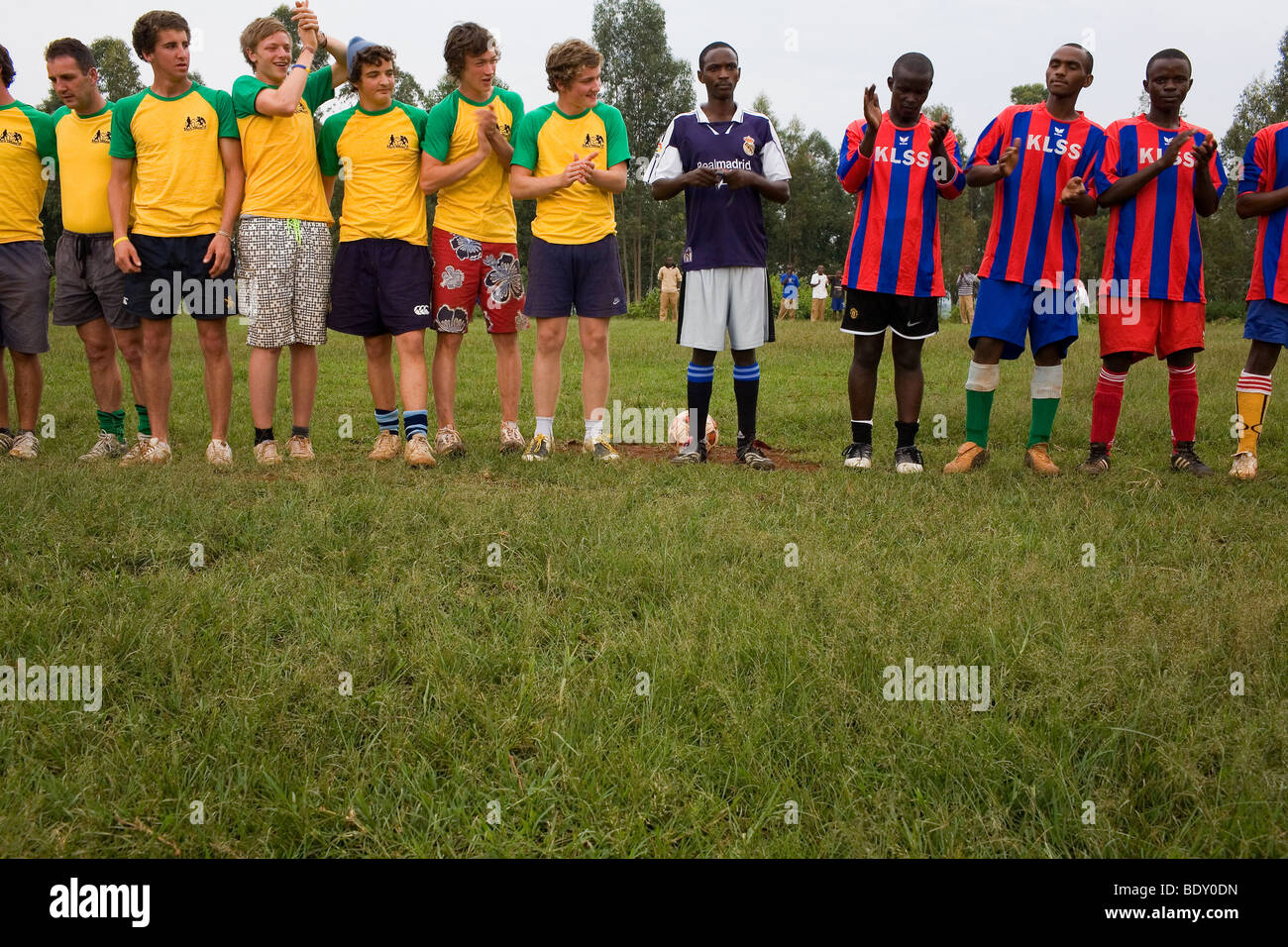 A line of white young men line up with the referee and a team of black ...