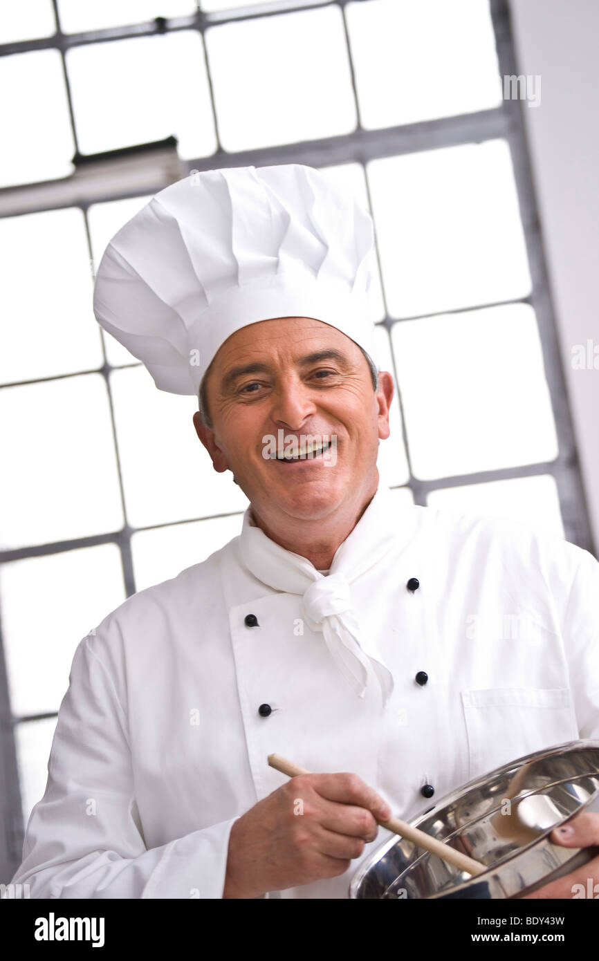 Chef wearing a chef's hat stirring in a saucepan Stock Photo - Alamy