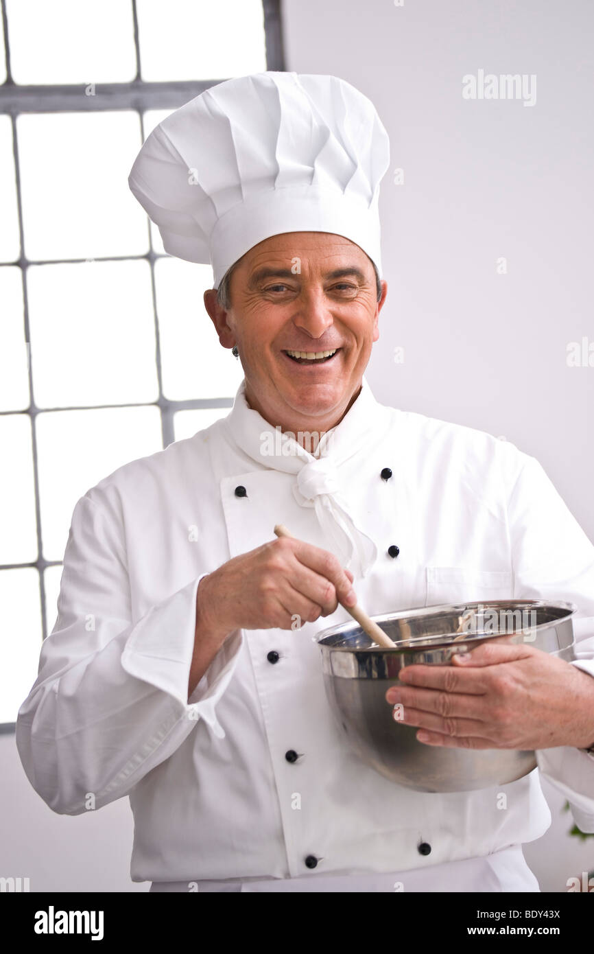 Chef wearing a chef's hat stirring in a saucepan Stock Photo - Alamy