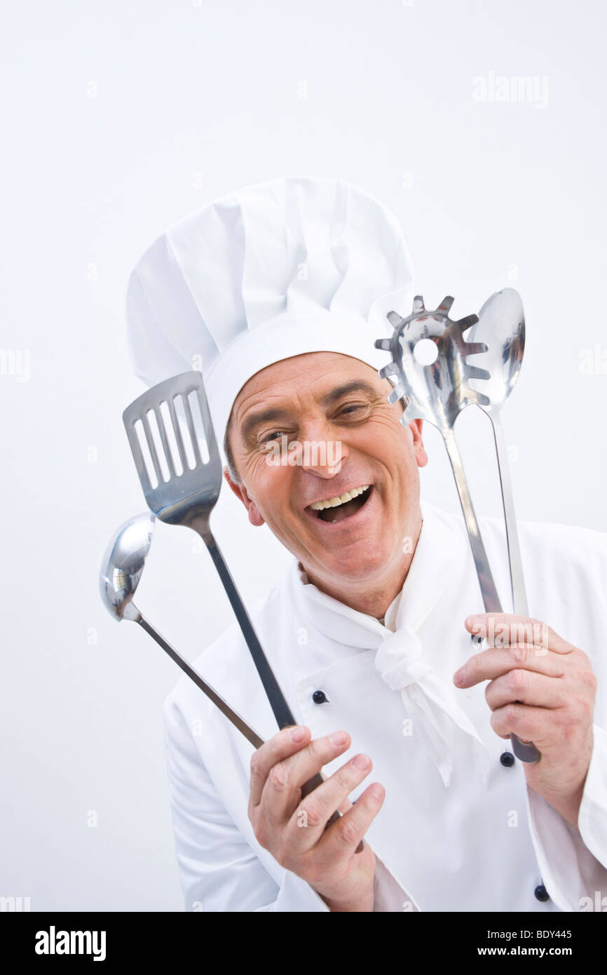 Chef wearing a chef's hat holding cooking utensils in his hands Stock ...