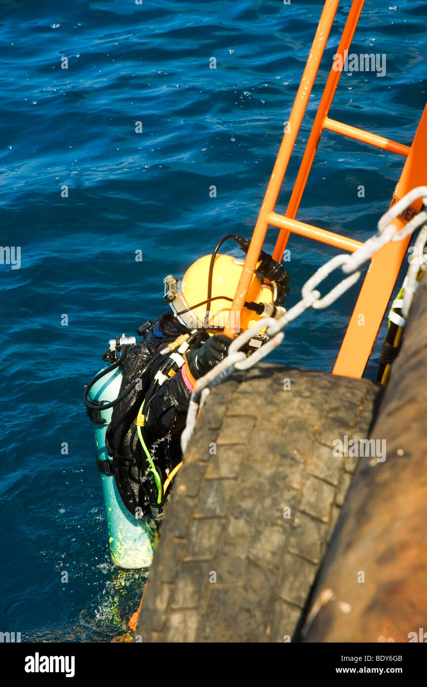 Commercial diver coming out of the Mediterranean sea. Cables from the ...