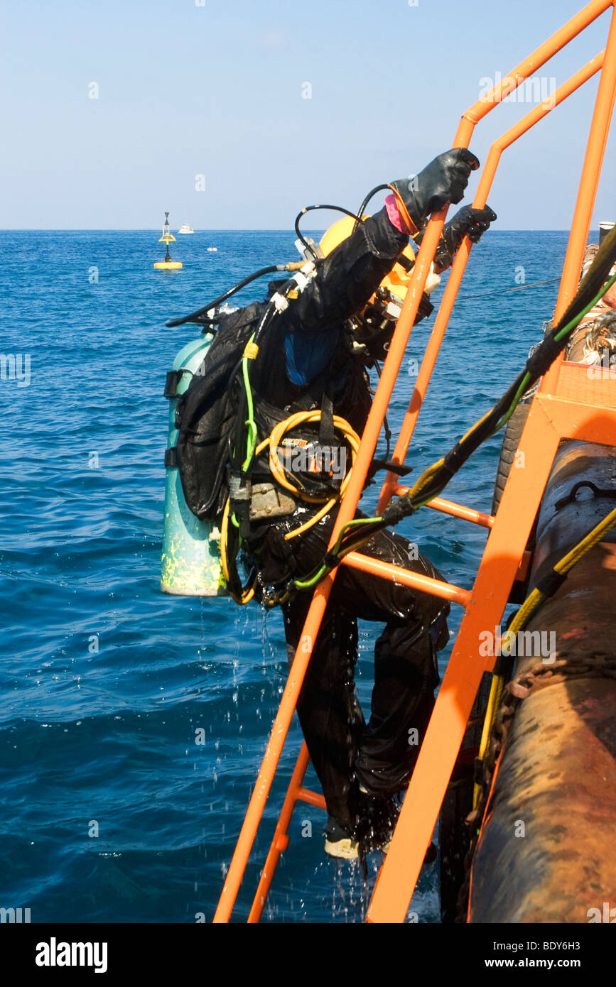 Commercial diver coming out of the Mediterranean sea. Cables from the ...