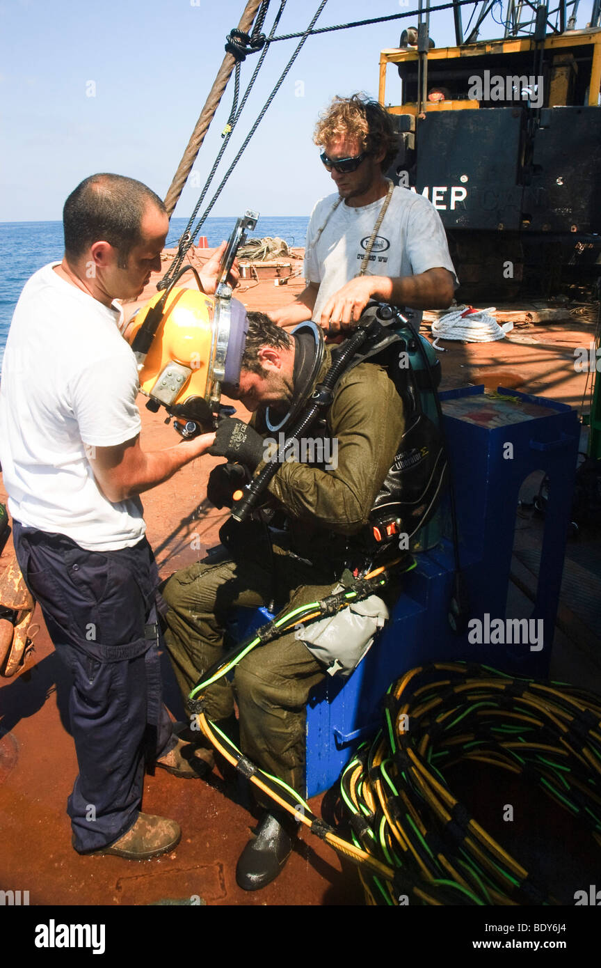 Commercial diver coming out of the Mediterranean sea. Cables from the ...