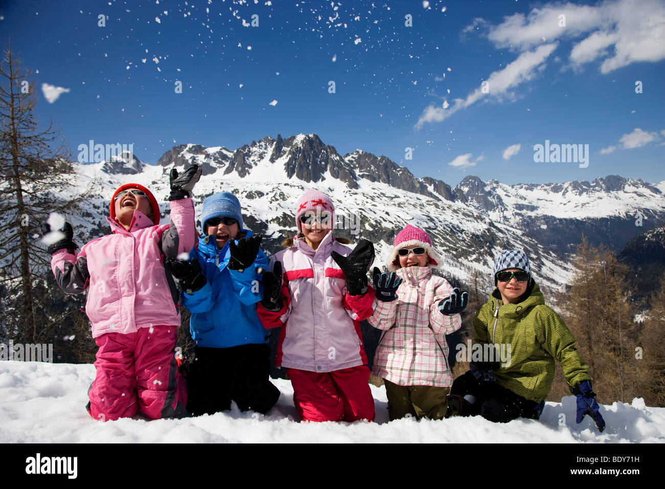 5 kids kneeling throwing snow Stock Photo - Alamy