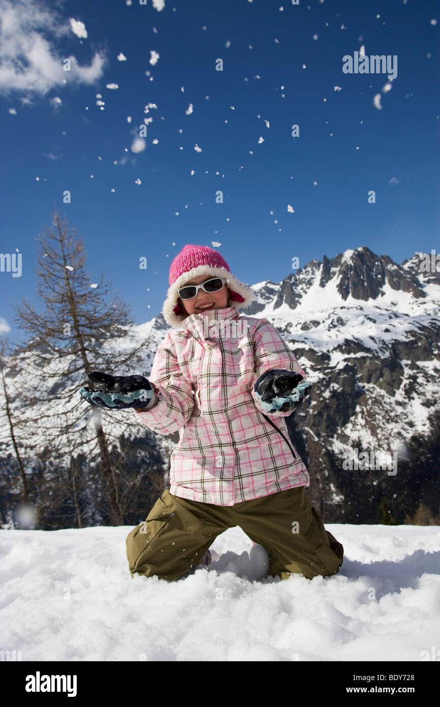 Girl kneeling down throwing snow Stock Photo - Alamy
