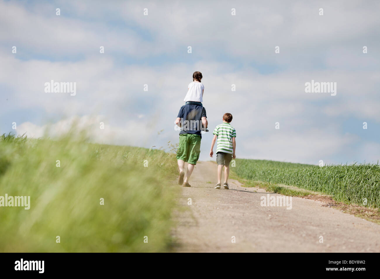 family of three walking up the road Stock Photo - Alamy