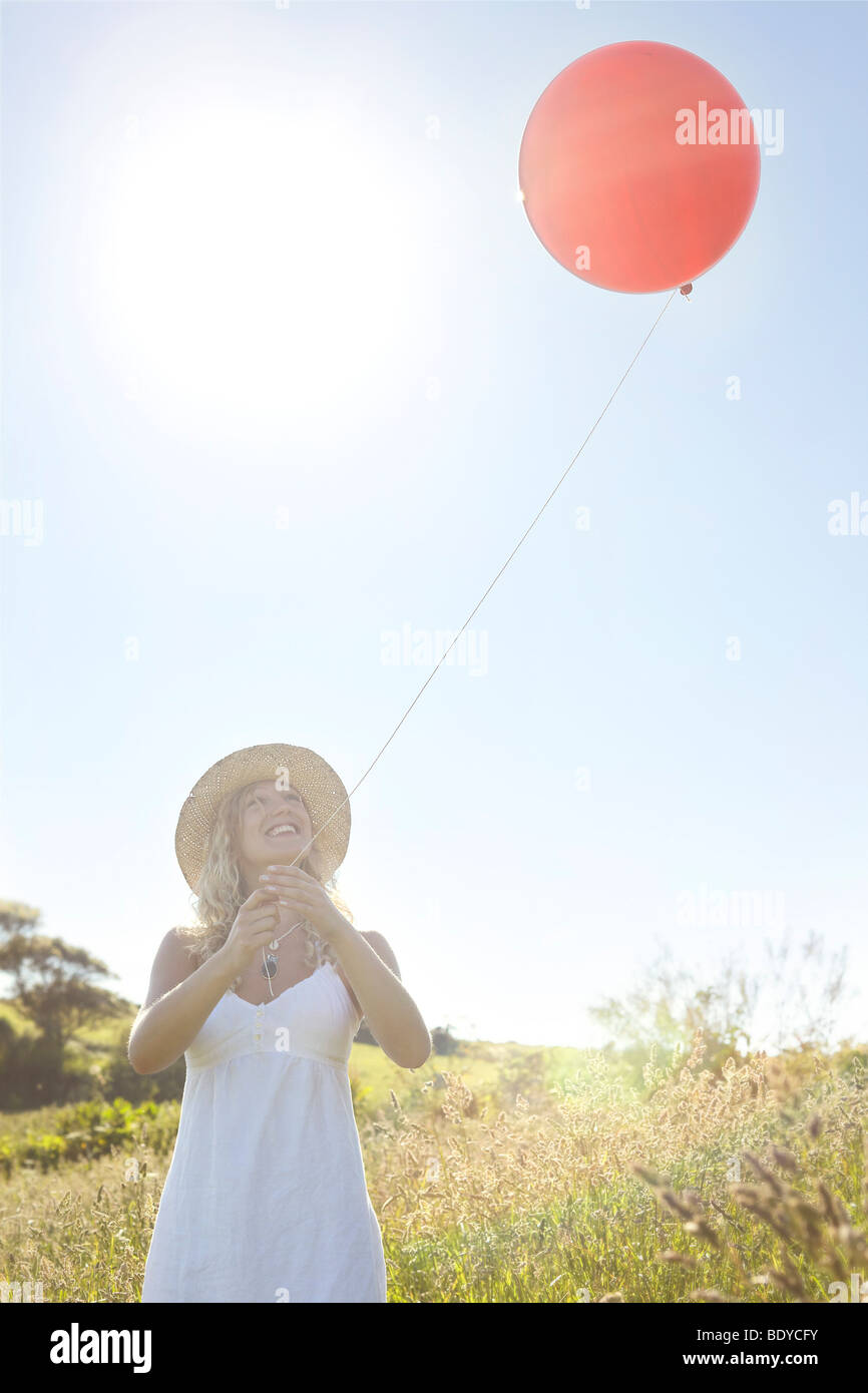 A girl in a field with a red balloon Stock Photo - Alamy