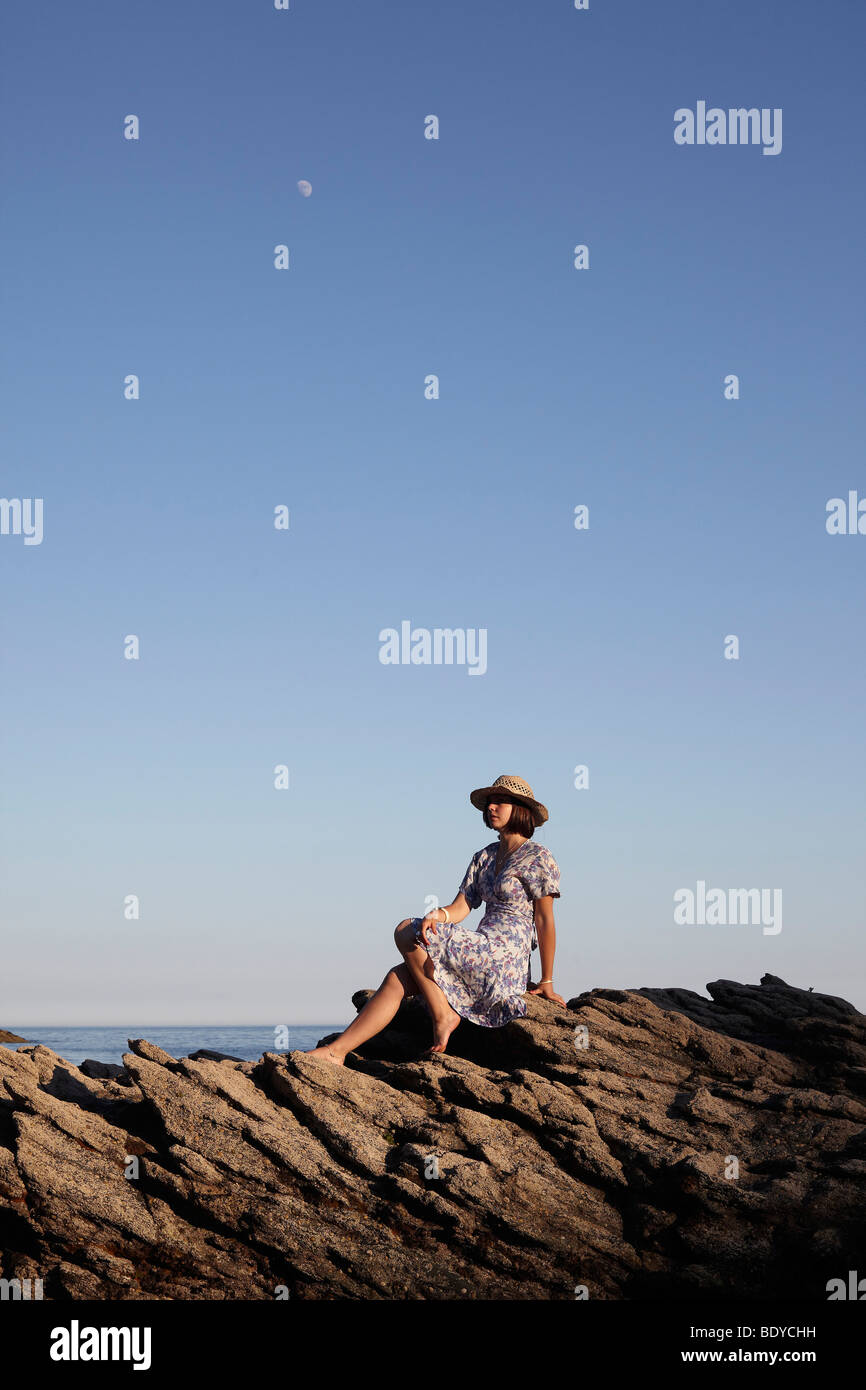 Girl sitting on rocks by the sea Stock Photo - Alamy