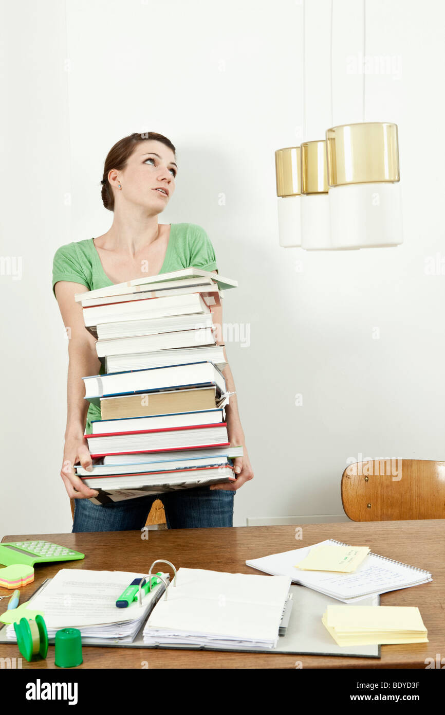 Female student carrying stack of books Stock Photo - Alamy