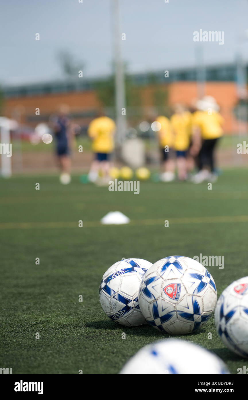 Footballs on a playing field with team in the background Stock Photo ...