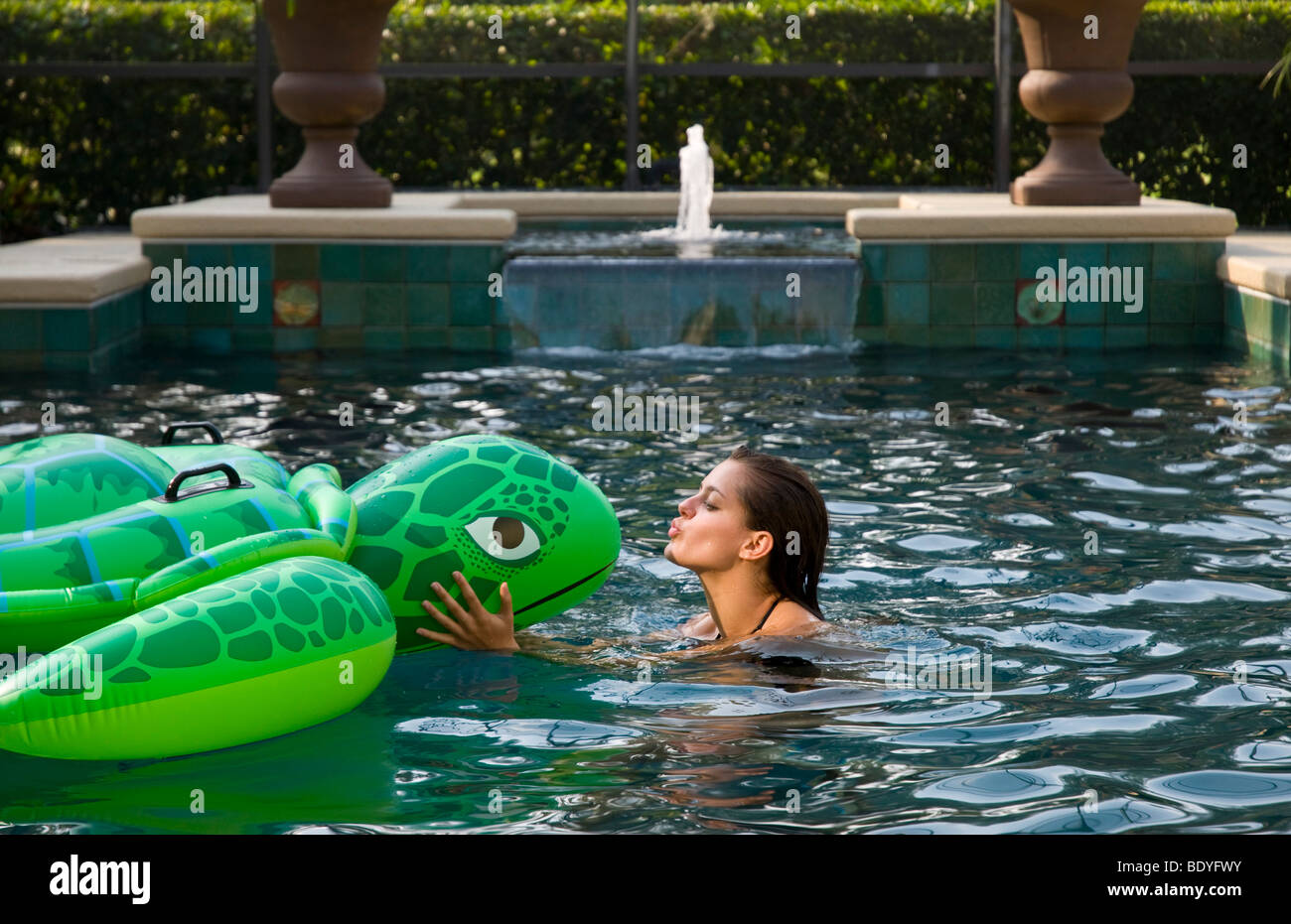 Beautiful teen lady in pool with turtle float Stock Photo - Alamy