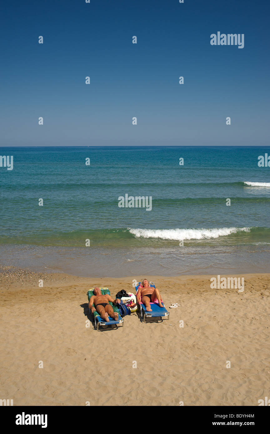Man and woman sunbathing on deserted sandy beach Crete Greece Stock ...
