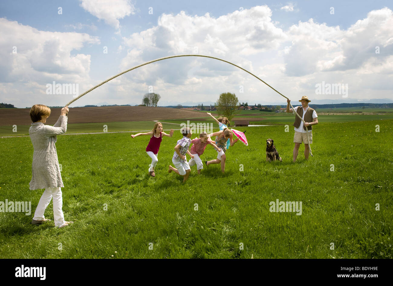 Happy family jump roping in countryside Stock Photo - Alamy