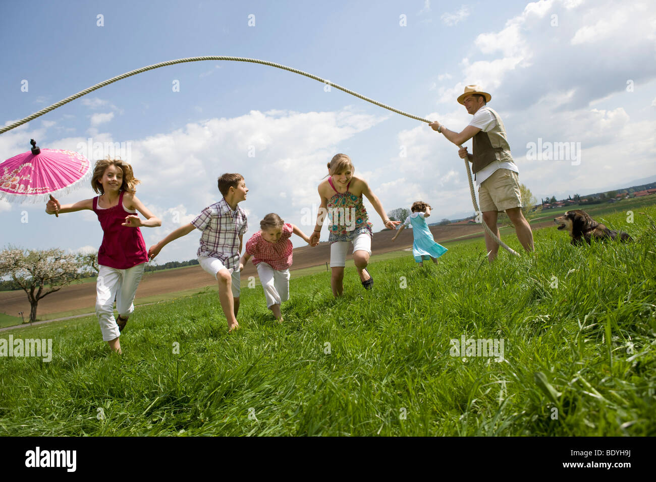 Happy family jump roping in countryside Stock Photo - Alamy