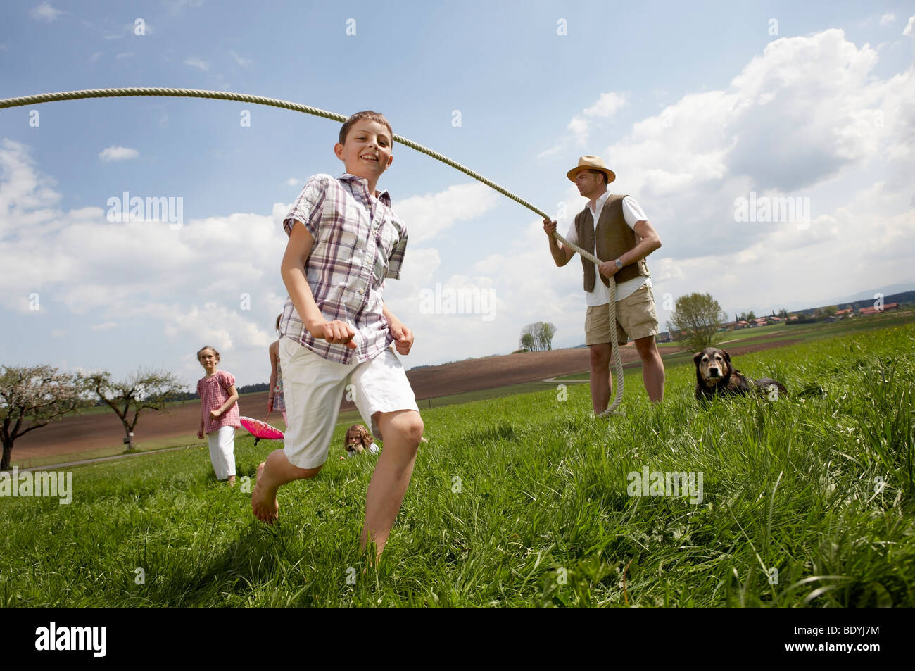 Happy family jump roping in countryside Stock Photo - Alamy