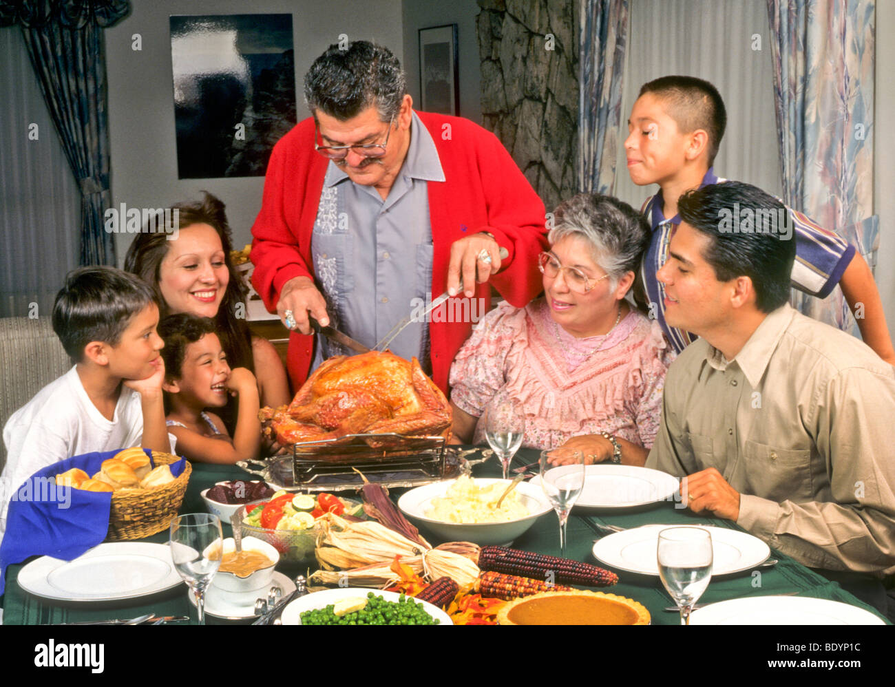 Latin family watches grandfather carve turkey thanksgiving meal ...