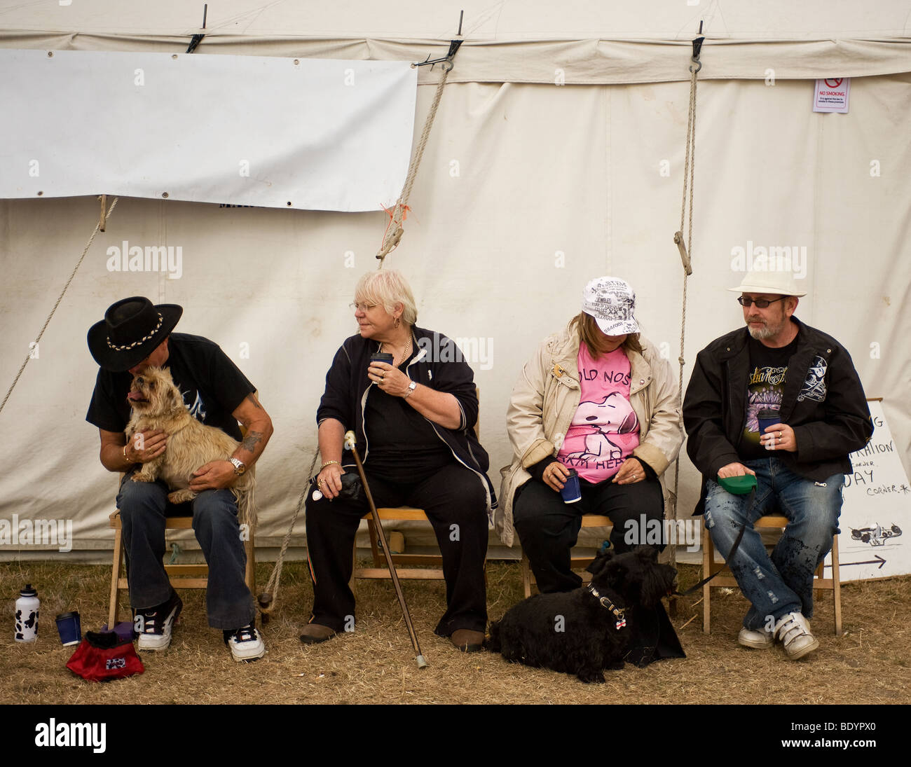 Dogs and their owners sitting outside a marquee at a country show in ...