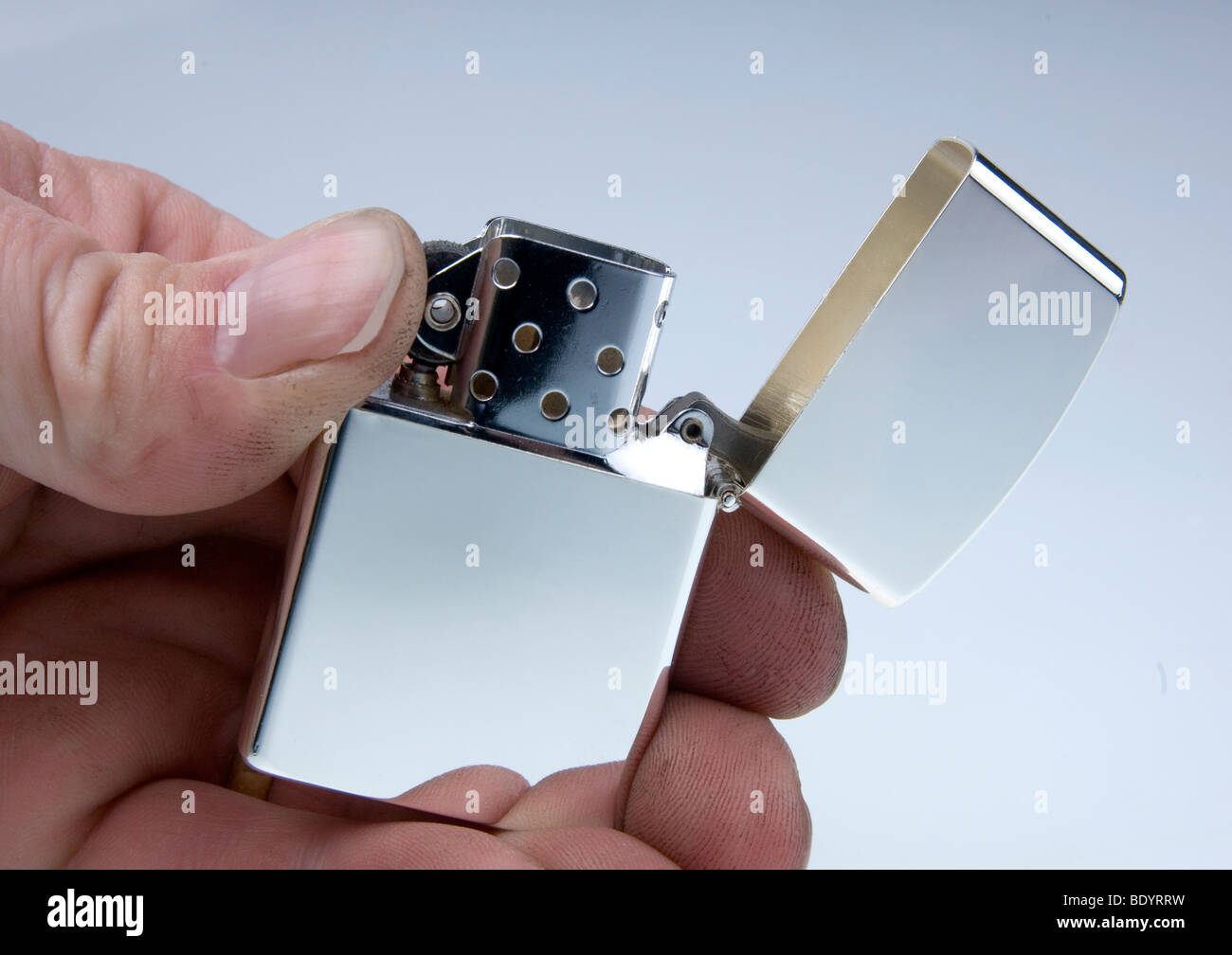 mans hand holding a very reflective silver lighter Stock Photo - Alamy