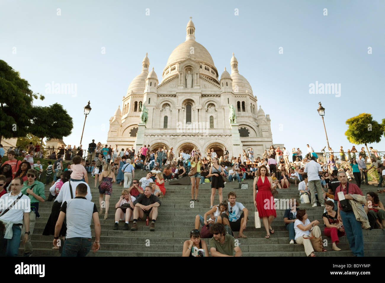 People sitting on the steps of the Sacre Coeur Church in the evening ...