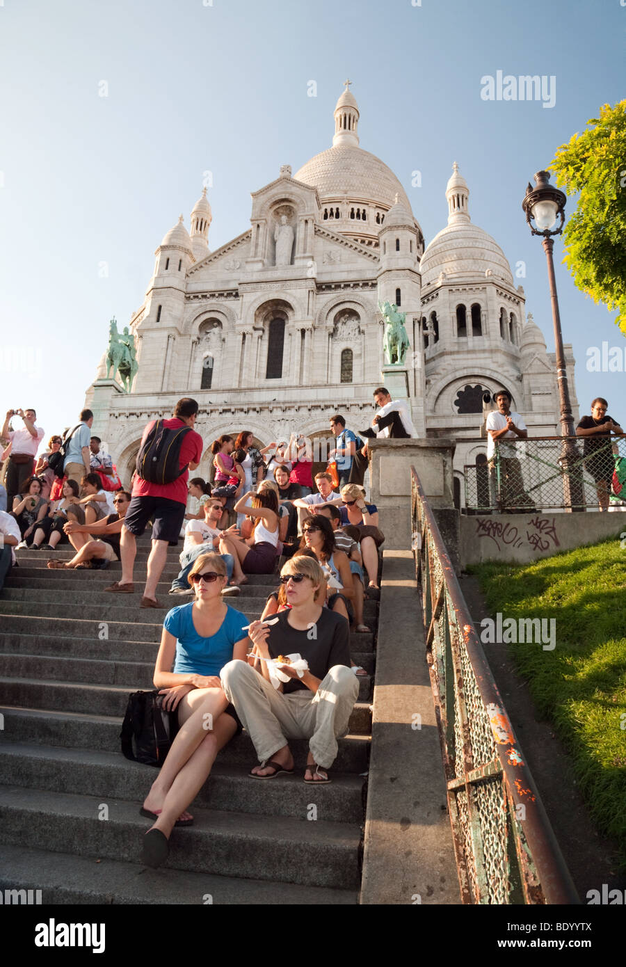 People sitting on the steps of the Sacre Coeur Church in the evening ...