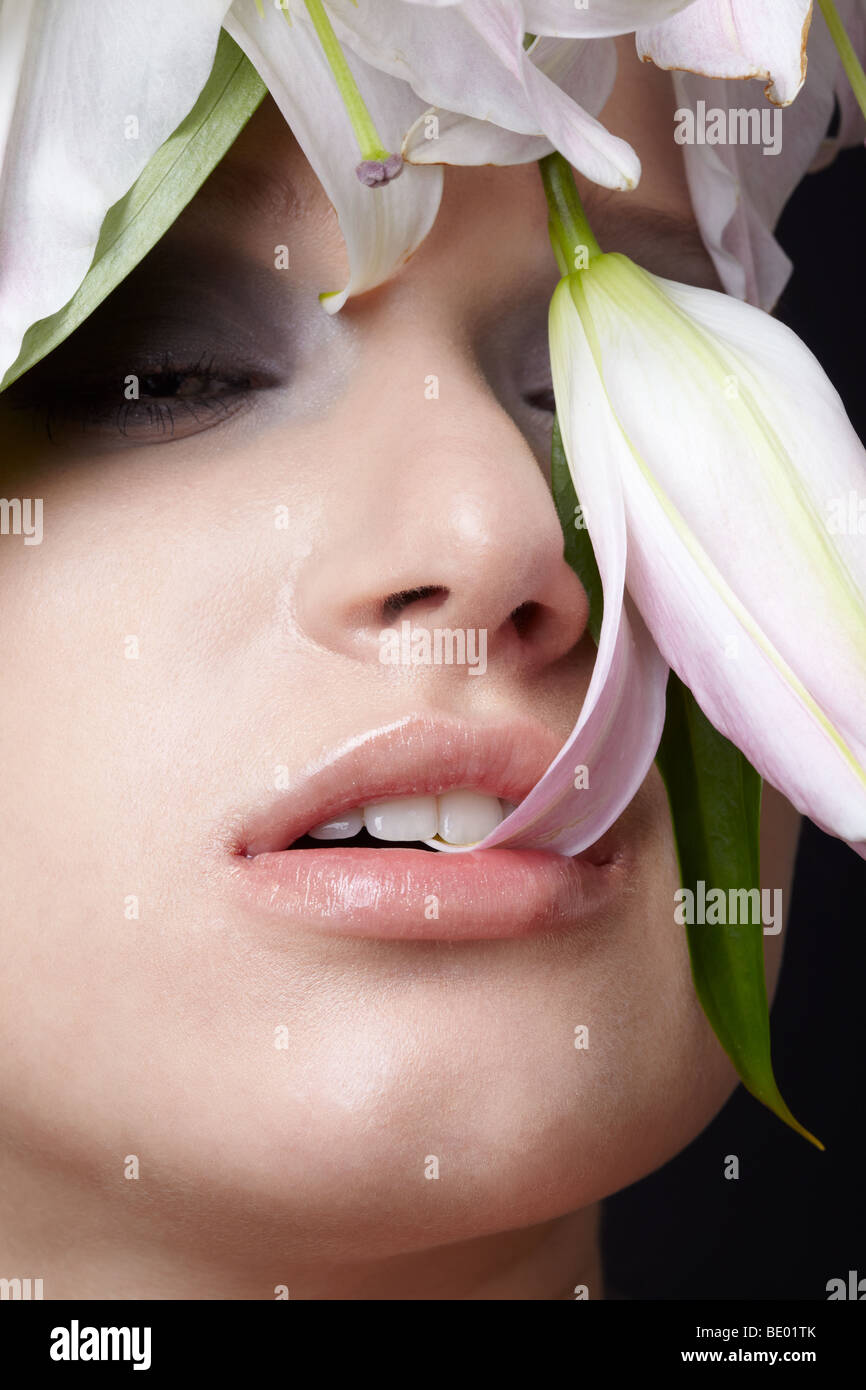 close-up portrait of half face of beautiful model nipping flower's ...