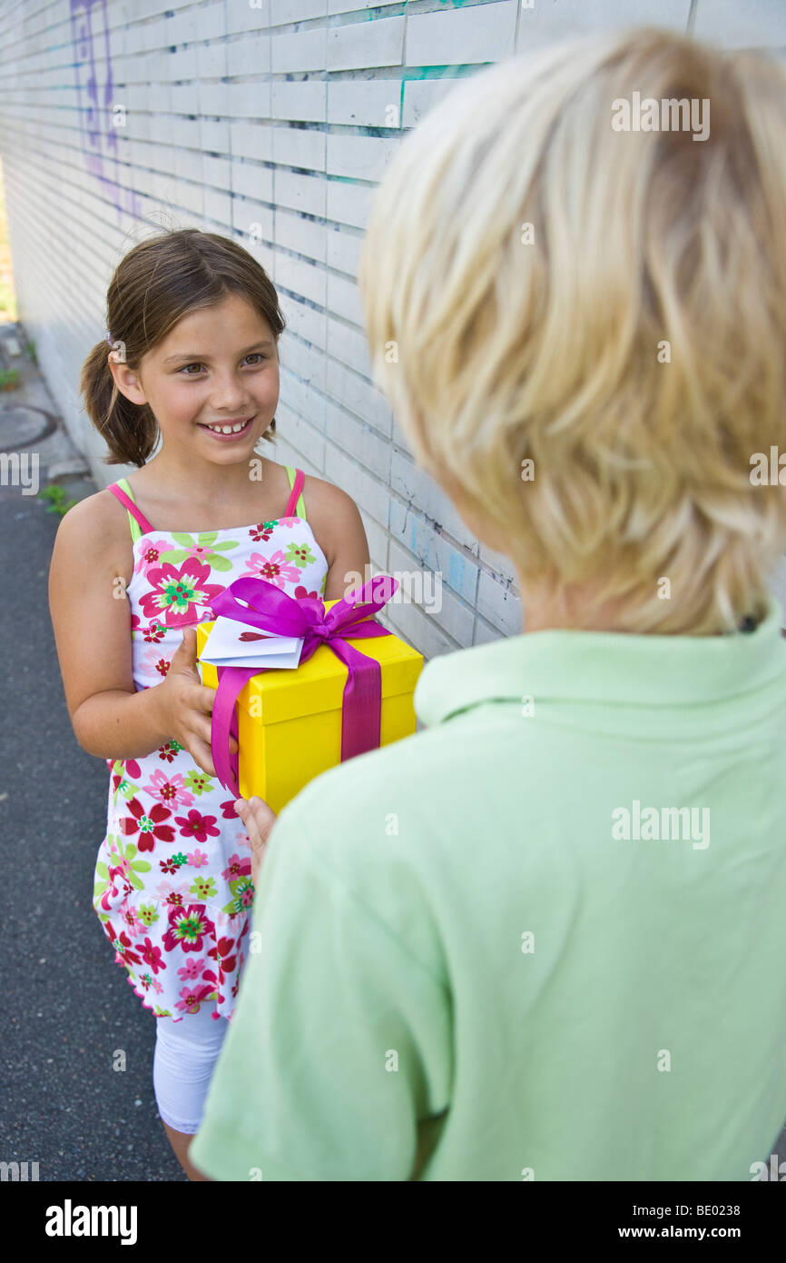 Young girl giving a boy a present, smiling Stock Photo - Alamy