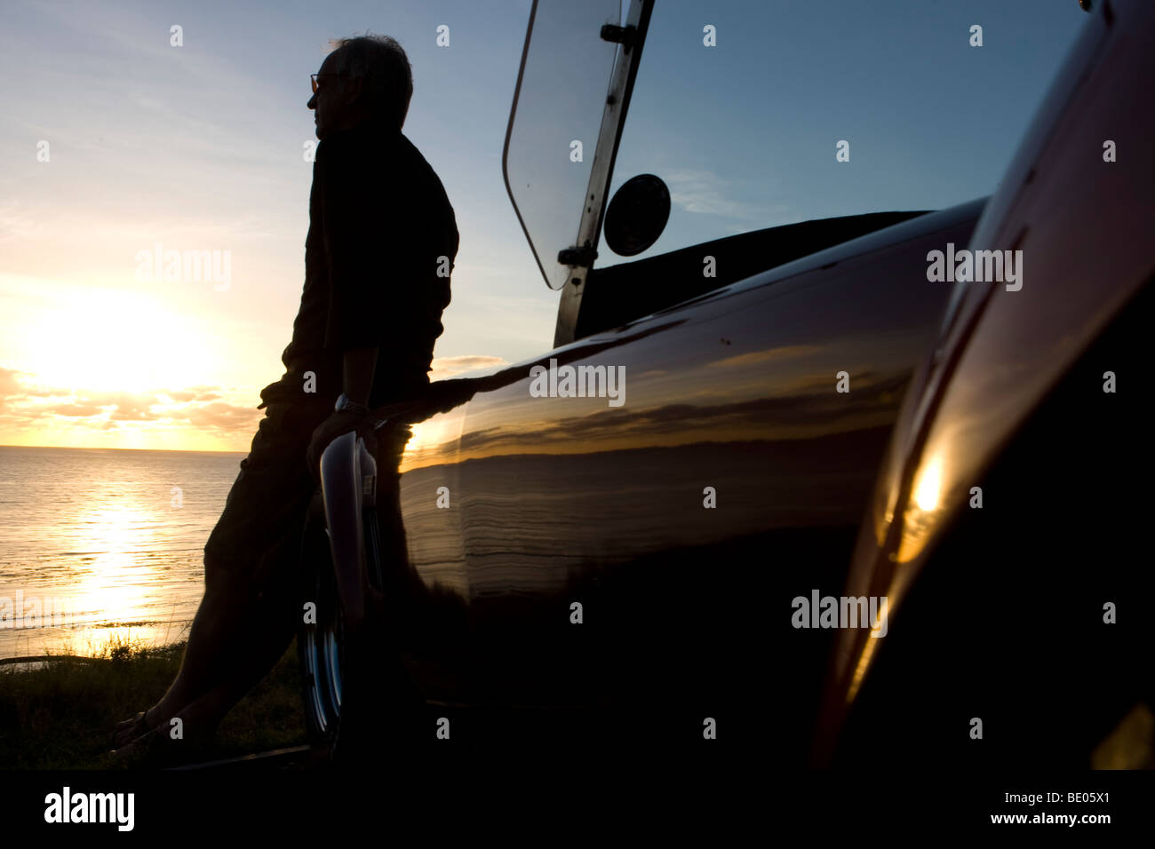 Older Man views sunset from car bonnet Stock Photo - Alamy
