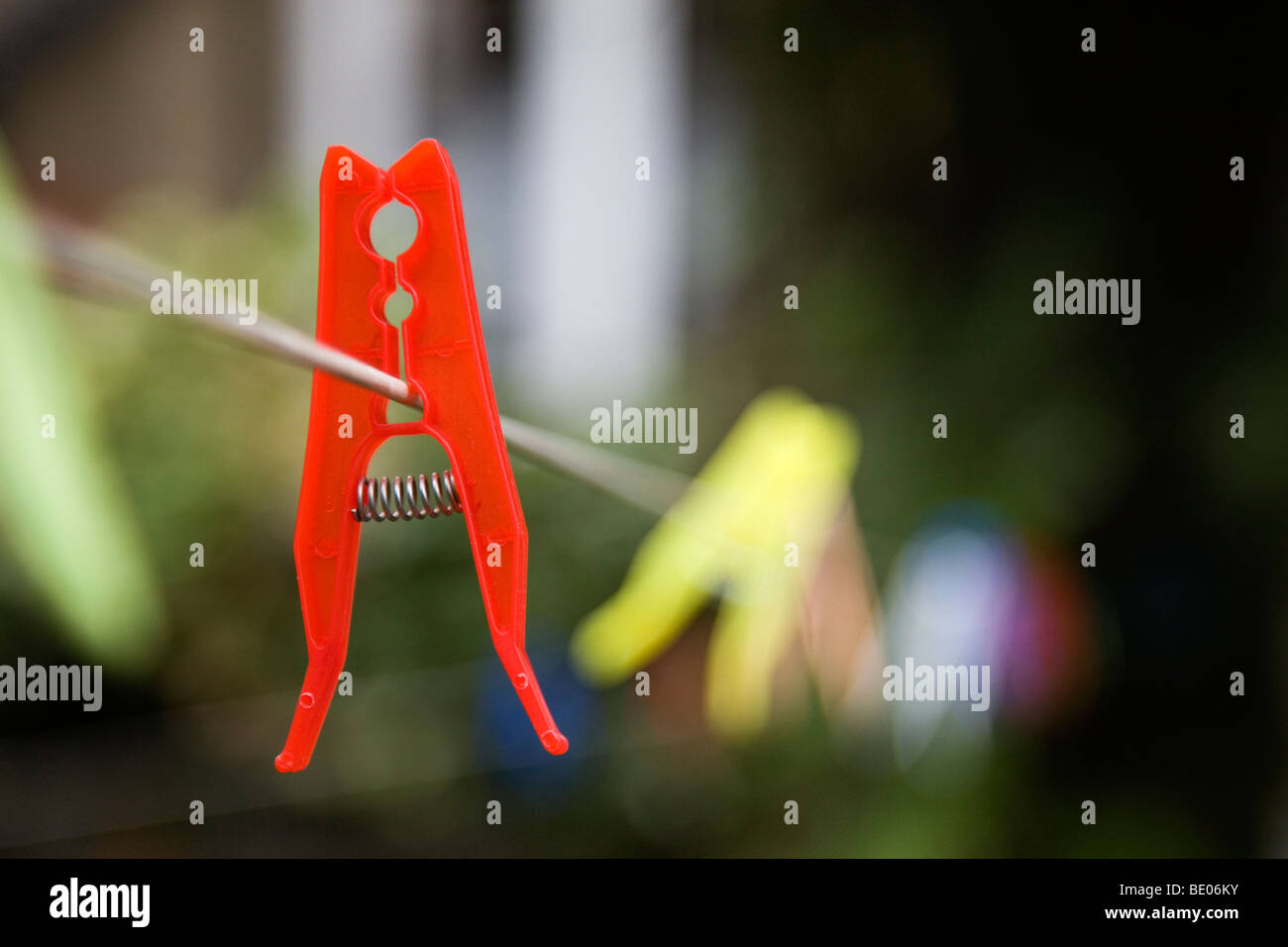 A red clothes peg on a washing line with a veru blurred background ...