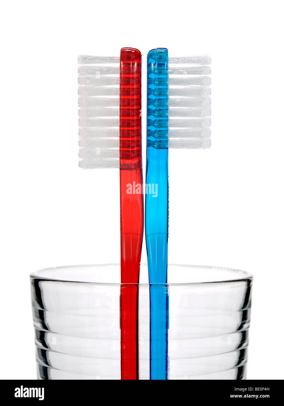 Two toothbrushes in a glass over white background Stock Photo - Alamy