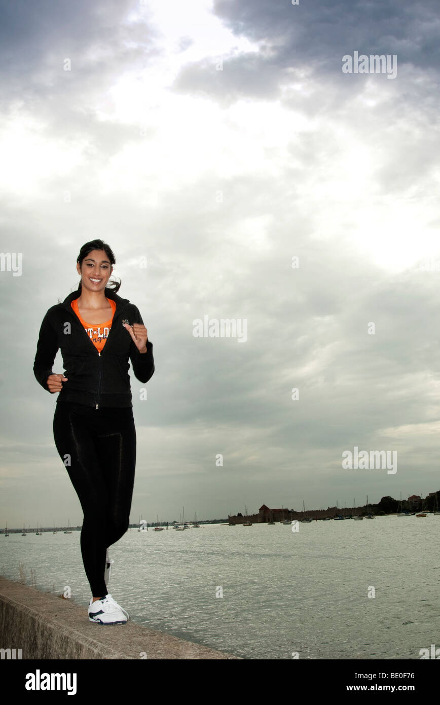 ethnic woman running along a wall Stock Photo - Alamy